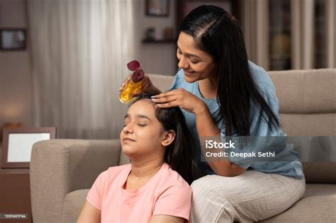 Madre Le Da Masaje De Cabeza De Aceite A Su Hija En Casa Foto De Stock