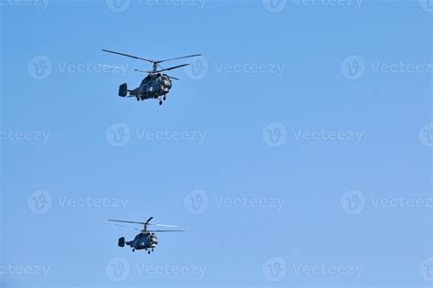Two Military Helicopters Flying In Vibrant Blue Sky Performing