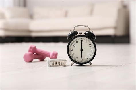 Premium Photo Alarm Clock Measuring Tape And Dumbbells On Wooden