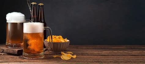 2 つのグラスに冷たいビールと暗い背景にポテトチップスのボウル プレミアム写真