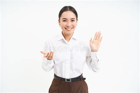 Portrait Of Beautiful Asian Woman Raises One Hand Smiles Friendly