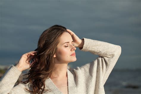 세련된 아가씨 갈색 머리 모델 바다 해변 야외에서 화장을 하고 긴 짙은 물결 모양의 헤어스타일을 하는 아름다움 여자 평온함 감정