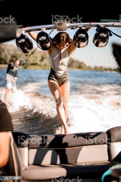 젊은 아름다운 여자는 모터 보트에 서서 남자 는 배경웨이크 보드에 타고 웨이크 보드에 대한 스톡 사진 및 기타 이미지 웨이크 보드 2명 갈색 머리 Istock