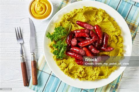 겨자 포크와 칼 위에서 수평 보기 평평한 평지 클로즈업흰색 나무 테이블에 흰색 접시에 튀긴 매운 소시지와 녹색 완두콩퓌레 0명에 대한 스톡 사진 및 기타 이미지 Istock