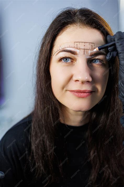 Premium Photo A Permanent Makeup Artist Marks A Womans Eyebrows With