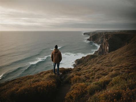 Premium Photo A Lone Figure Stands On The Edge Of A Cliff Overlooking