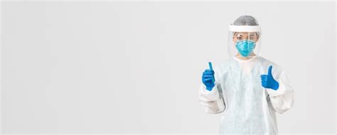Covid 19、コロナウイルス病、医療従事者の概念。自信を持って真面目なアジアの女性医師、個人用保護具の技術研究所の従業員は親指を立てて