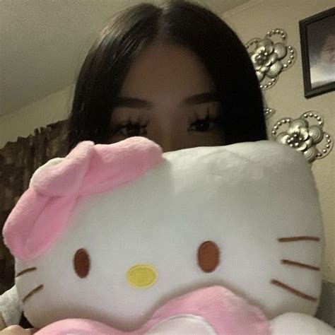 A Woman Holding A Hello Kitty Pillow In Front Of Her Face
