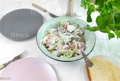 깊은 접시에 신선한 야채샐러드 오이와 토마토 사워 크림 흰색 식탁보와 테이블 2 빈 접시 빵 조각 서빙 테이블 0명에 대한 스톡