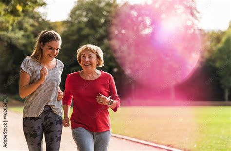 Granddaughter And Grandmother Having Fun Jogging Together In The Park