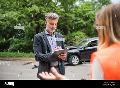 An Insurance Agent Talking To A Woman Outside On The Road After A Car