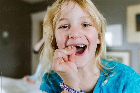 Young Girl Wiggling Loose Tooth By Stocksy Contributor Carey Shaw