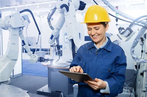 woman engineer uses a digital tablet to control robots in a smart factory stock image image