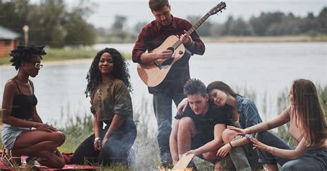 기타와 함께 서서 한 무리의 사람들이 해변에서 피크닉을 즐깁니다 친구들은 주말에 즐거운 시간을 보냅니다 사진 Unsplash의 우정 이미지