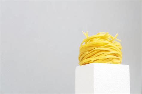 이탈리아 파스타 흰색 연단에 있는 스파게티 카펠리니는 회색 배경 측면 보기로 고립되어 있습니다 둥지의 형태로 파스타 파스타의