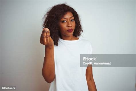 고립 된 흰색 배경 위에 서있는 티셔츠를 입은 젊은 아프리카 계 미국인 여성은 손과 손가락으로 자신감있는 표정으로 이탈리아제스처를 하고 있습니다 T 셔츠에 대한 스톡 사진
