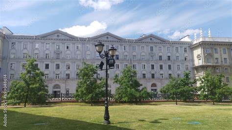 In The City Square Trees Grow On Grassy Lawns And Metal Poles With Lanterns Are Installed The