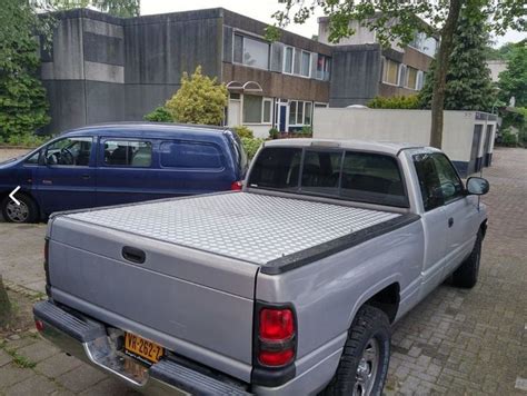 The Truck Is Parked On The Side Of The Road Next To Another Car In