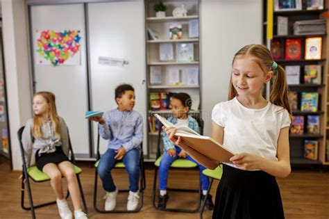 Schoolgirl Standing In Middle Of Classroom And Answering Question In