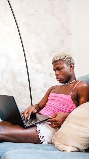 집에서 일하는 소파에서 노트북을 사용하는 심각한 흑인 트랜스젠더 여성 컴퓨터에 대한 스톡 사진 및 기타 이미지 컴퓨터 트랜스젠더 보기 정적 활동 Istock