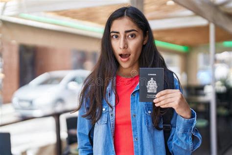 Young Teenager Girl Holding Canada Passport Scared And Amazed With Open
