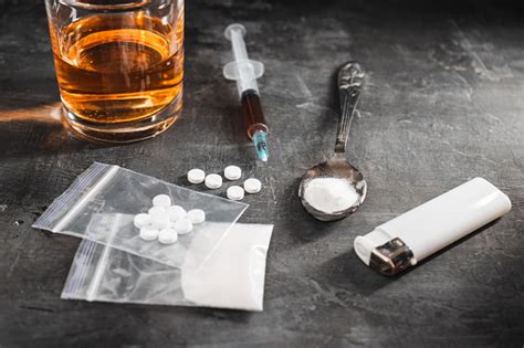 暗い背景にグラスの中のアルコール飲料薬の投与量が入った注射器透明な袋の中の白い錠剤スプーンの中の麻薬粉末中毒と悪い習慣の概念 Lsdの