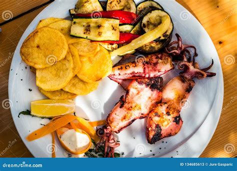 Grilled Squid With Potato Chips Vegetables On A White Plate Stock