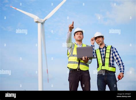 Two Asian Engineers Discussing And Checking Turbines On Wind Turbine Farm Renewable Energy