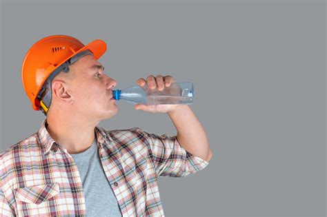 회색 배경에 서 있는 플라스틱 병에서 물을 마시는 피곤한 노동자 카피스페이스 30 34세에 대한 스톡 사진 및 기타 이미지 30 34세 30 39세 건강한 생활방식