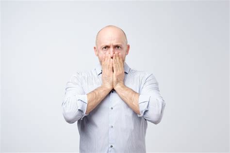 Portrait Of A Shocked Young Man Covering His Mouth With Hands Stock