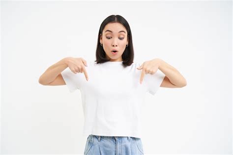 Retrato De Menina Asiática Com Rosto Surpreso Aponta Para Baixo Olha