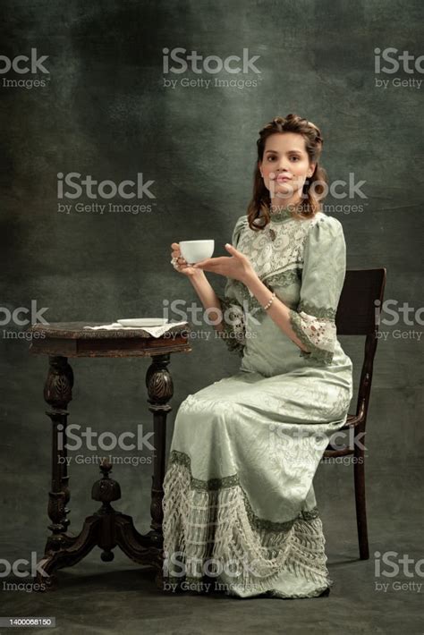 어두운 배경에 고립 된 차를 마시는 중세 스타일의 회색 드레스를 입은 어린 아름다운 소녀의 빈티지 초상화 시대 개념 플랑드르 스타일의 비교 예술 아름다움 20 24세에 대한