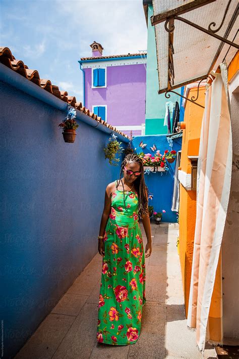 An Elegant Woman Walks In A Colorful Alley On A Sunny Day By Stocksy