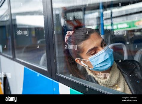 A Woman Sleeping With Her Head Against A Window Of A Bus Wearing A