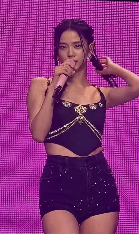 A Woman In Black Shorts And Crop Top Holding A Microphone To Her Mouth