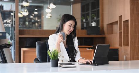 커피를 마시고 사무실에서 태블릿 컴퓨터로 작업하는 사업가의 가로 이미지 사진 Unsplash의 태국 이미지