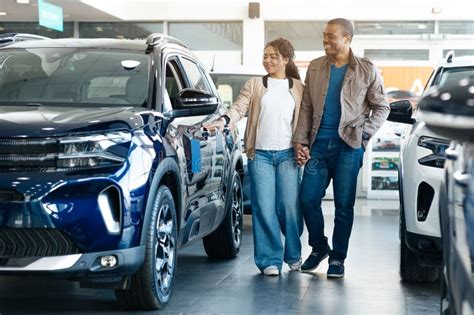 Couple Choosing New Car Together Standing Near Luxury Vehicle In Auto