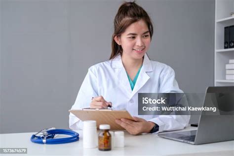 병원 사무실에서 노트북 문서 알약을 들고 일하는 행복한 여의사 노트북을 들고 일하는 하얀 의료복을 입은 젊은 아시아 여성 의사 30 34세에 대한 스톡 사진 및 기타 이미지