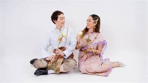 Asian Couple In Traditional Thai Costume Holding Lotus And Looking At