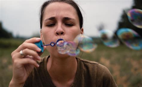 Premium Photo The Girl Blows Soap Bubbles A Young Woman Sits In