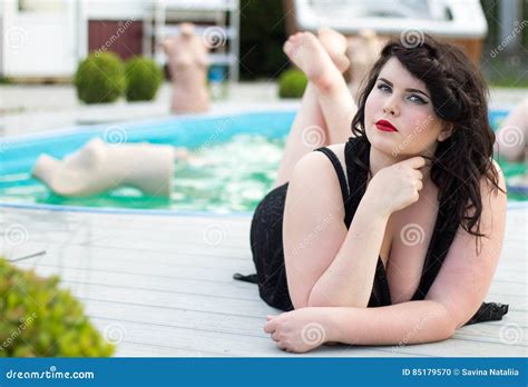 Young Beautiful Plus Size Model Lying Near The Outdoors Pool Stock