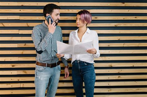 야외에서 스마트폰 기기로 전화하는 종이 스케치 자랑 Ceo를 보여주는 젊은 여성 비서 벽에 서있는 청사진 을 구축에 남성과 여성 동료의 협력 2명에 대한 스톡 사진 및 기타