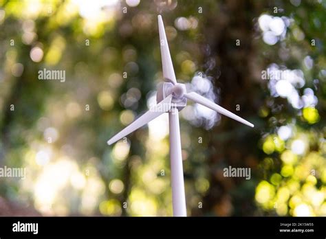 Portable White Solar Powered Windmill Toy Placed In Lush Green Forest