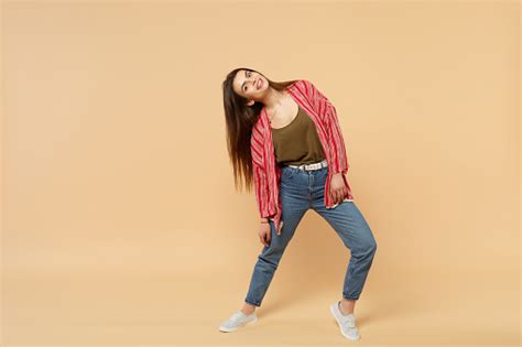 캐주얼에 서 있는 쾌활 한 예쁜 젊은 여자의 초상화 스튜디오에서 파스텔 베이지색 벽 배경에 고립 된 카메라를 찾고 사람들은