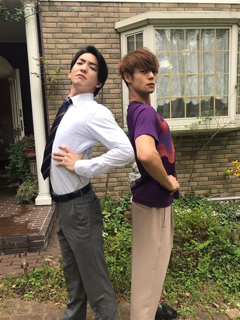 Two Men Standing Next To Each Other In Front Of A House