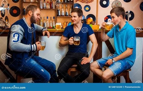 Tres Hombres Que Hablan Y Que Beben La Cerveza En Barra Foto De Archivo