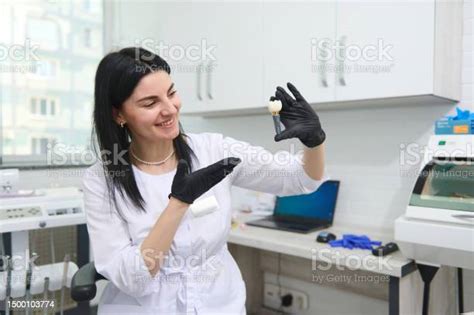경험이 풍부한 치과 의사가 인간 치아의 모델을 들고 의치 또는 치과 임플란트 설치의 메커니즘을 설명합니다 건강관리와 의술에 대한