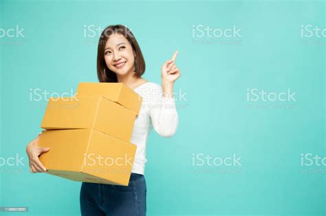 행복한 아시아 여자 들고 패키지 소포 상자 와 가리키는 손가락 에 빈 복사 공간 고립 된 밝은 녹색 배경 배달 택배 및 배송