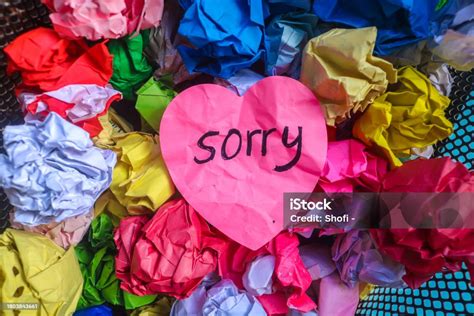 구겨진 종이로 가득 찬 쓰레기통에 하트 모양의 분홍색 포스트잇에 적힌 미안하다는 단어 메모로 사과하는 개념 개념에 대한 스톡