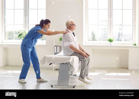 Senior Man With Back Pain Sitting On Massage Table While